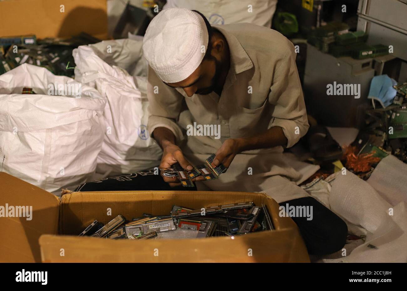A worker recycles electronic waste or e-waste from computers at a workshop in New Delhi Stock ...
