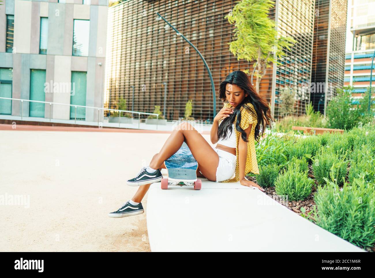 Pretty Athletic Girl Sitting With A Longboard In Modern City Stock