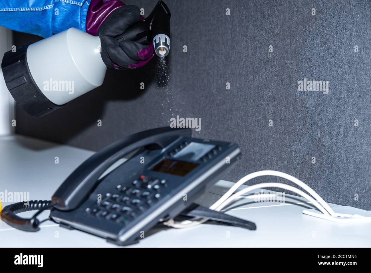 A hand holds a sprayer that contains a disinfectant agent for ...