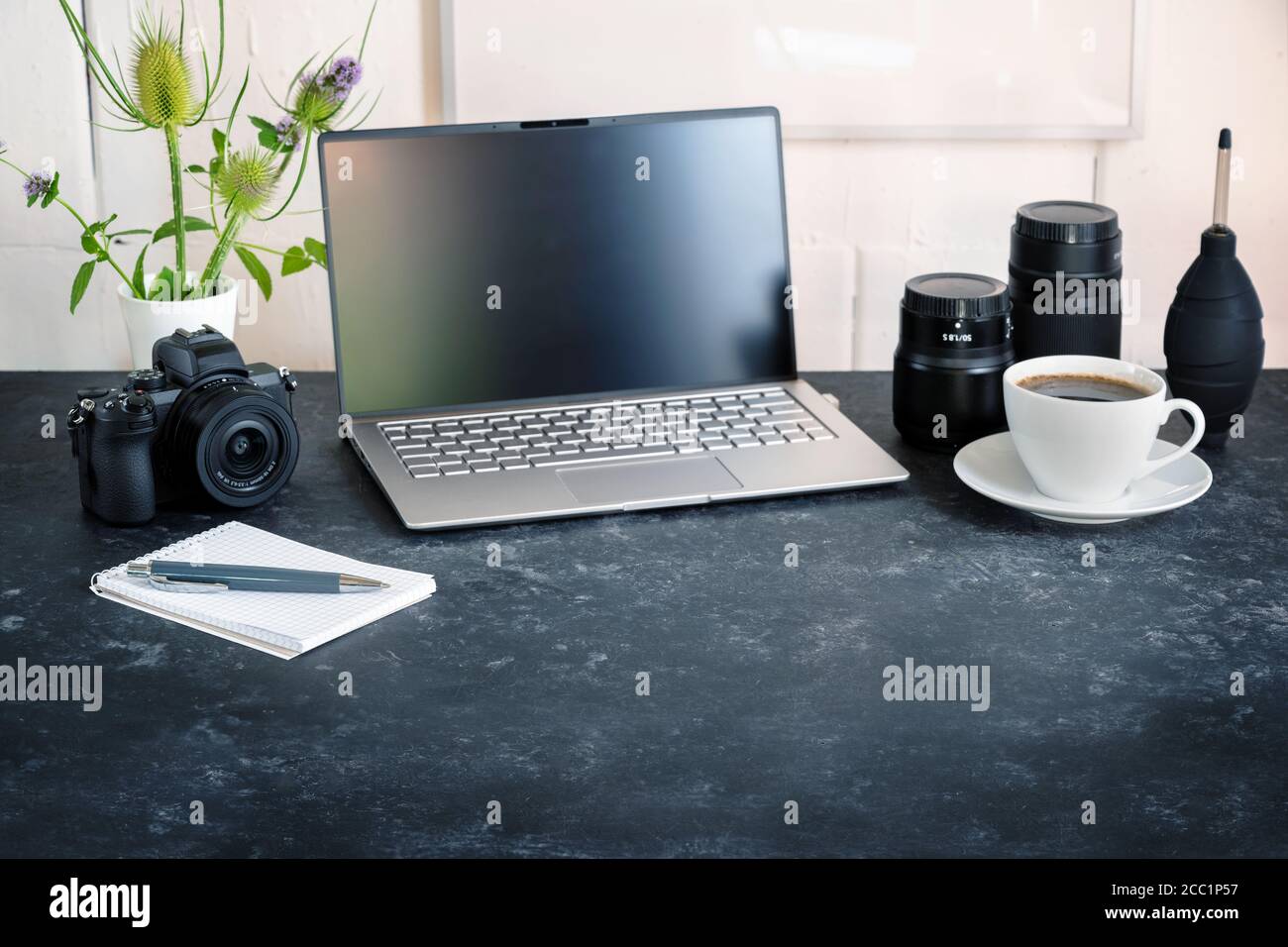 Office desk of a photographer with laptop, camera, lenses and a coffee ...