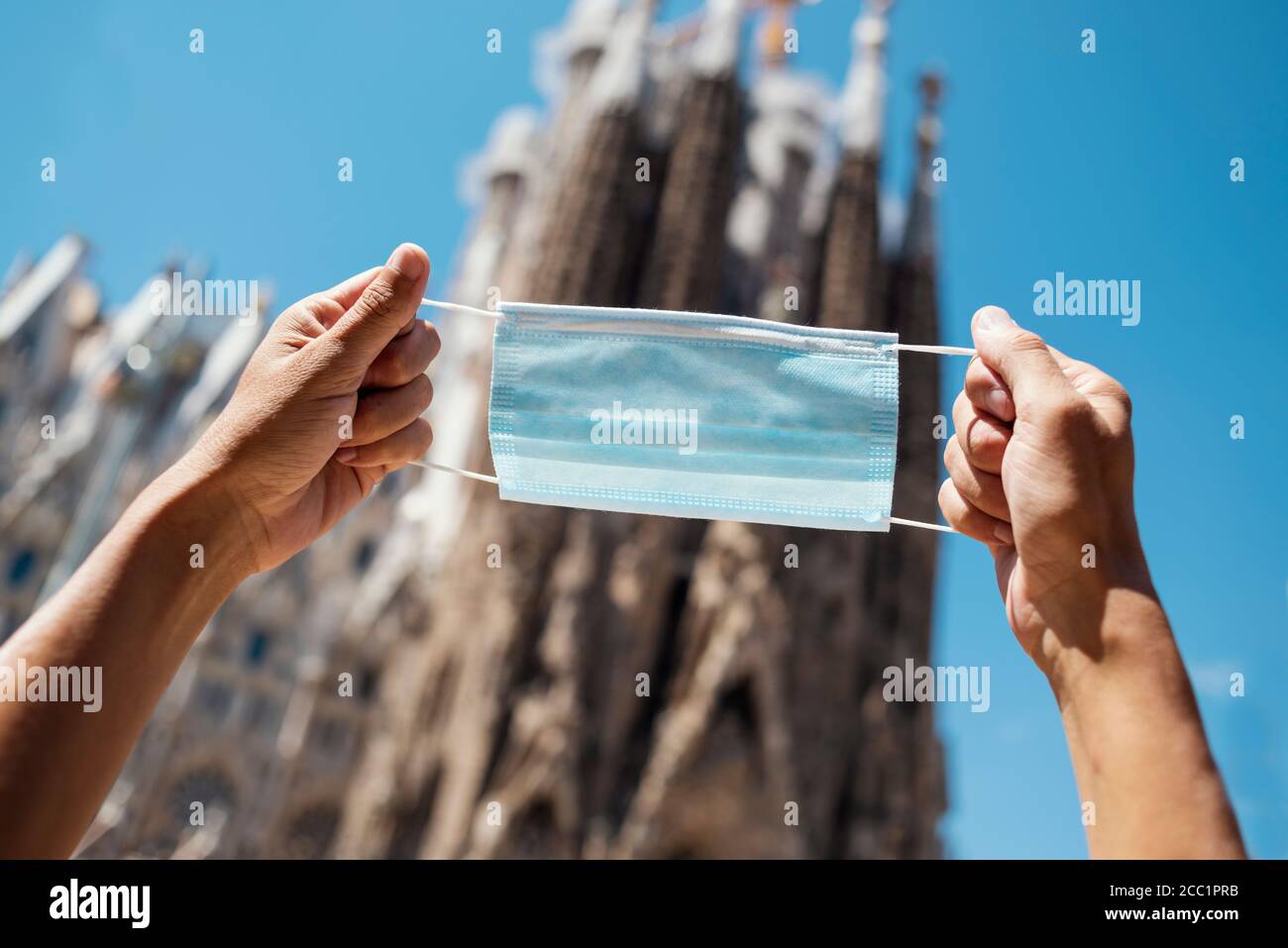 closeup of a man holding a blue face mask in front of La Sagrada ...
