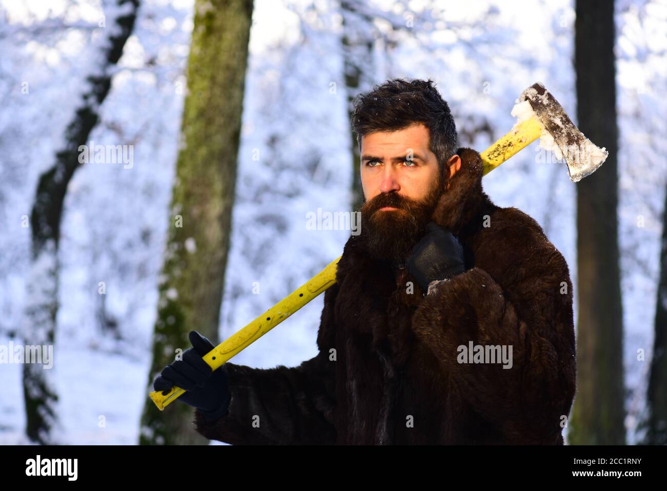 Frozen woodsman concept. Man in fur coat in the forest with axe on ...