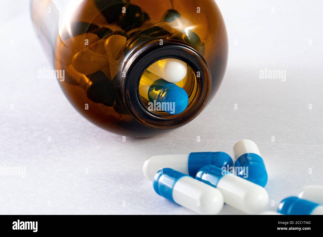 Medicine tablets inside and outside an amber glass bottle on an white ...