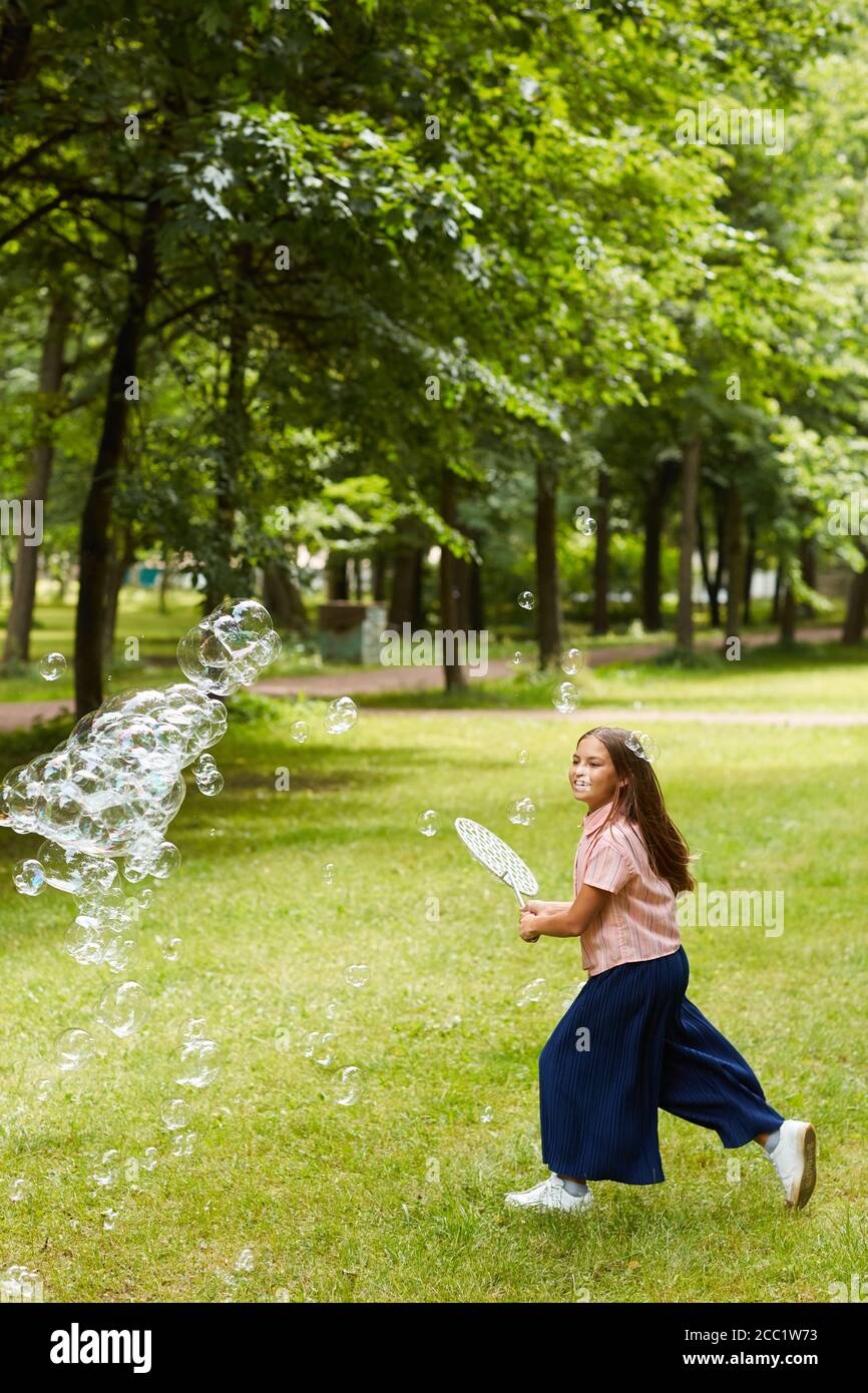 Vertical full length portrait of carefree girl running in park outdoors ...