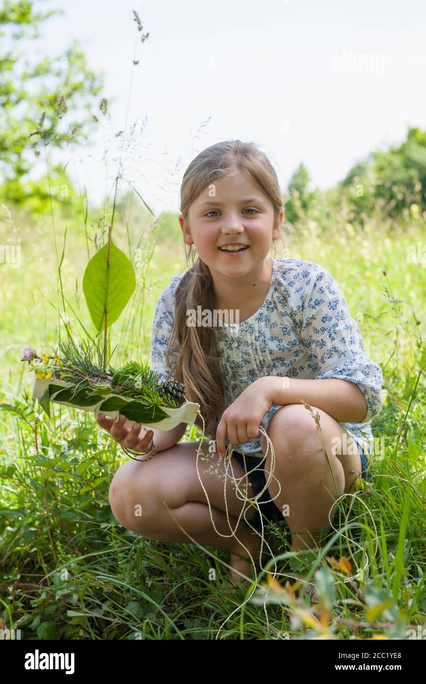 Germany, Bavaria, Munich, Portrait of girl holding self made boat ...