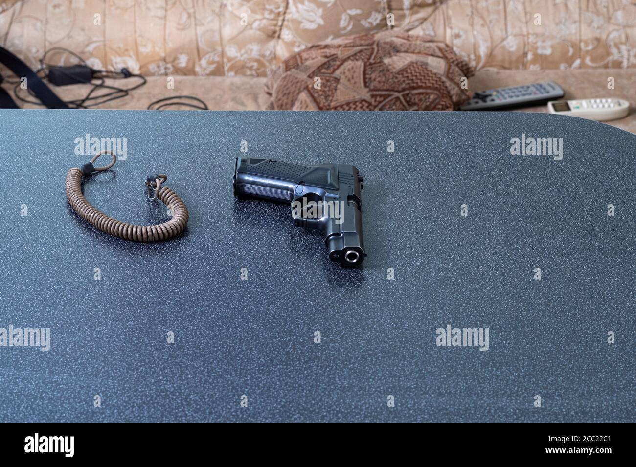 The gun is on the table. Pistol and sling on the home table. Storing a ...