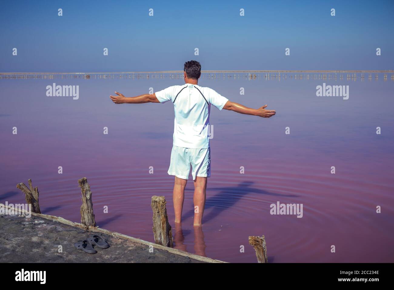 Brunet man relaxing on pink salty Sivash Lake near Azov Sea, colored by ...