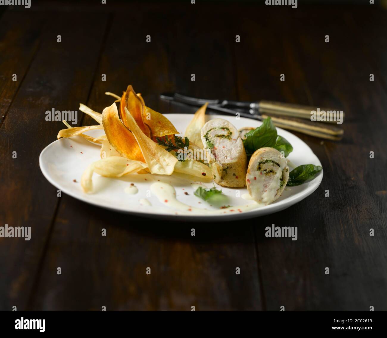 Plate of chicken roulade with chips on wooden table, close up Stock ...