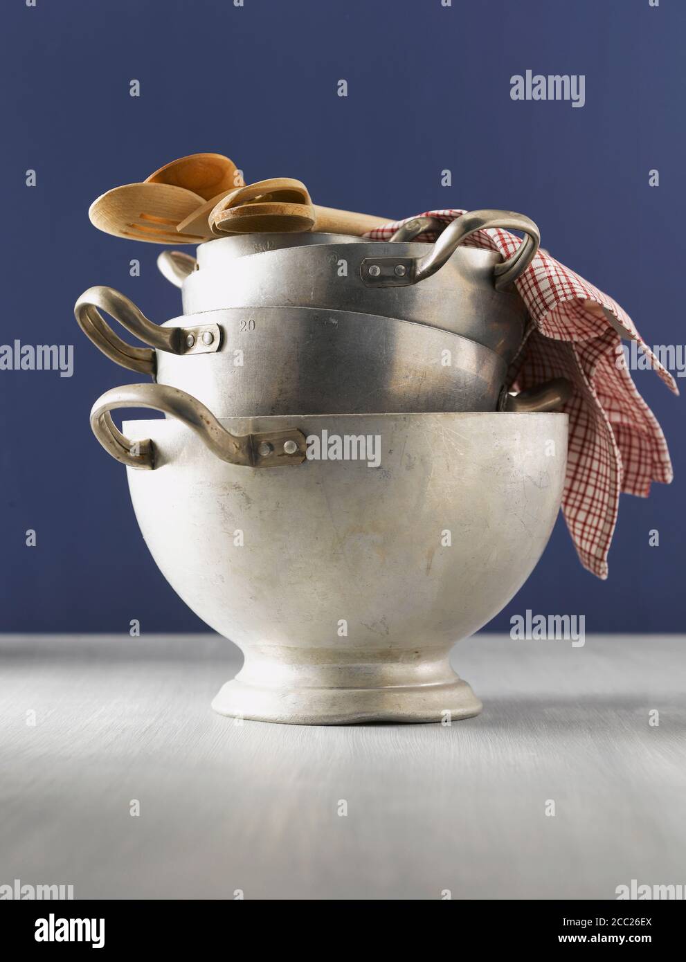 Stacked aluminium pots, wooden spoons and dishcloth Stock Photo - Alamy