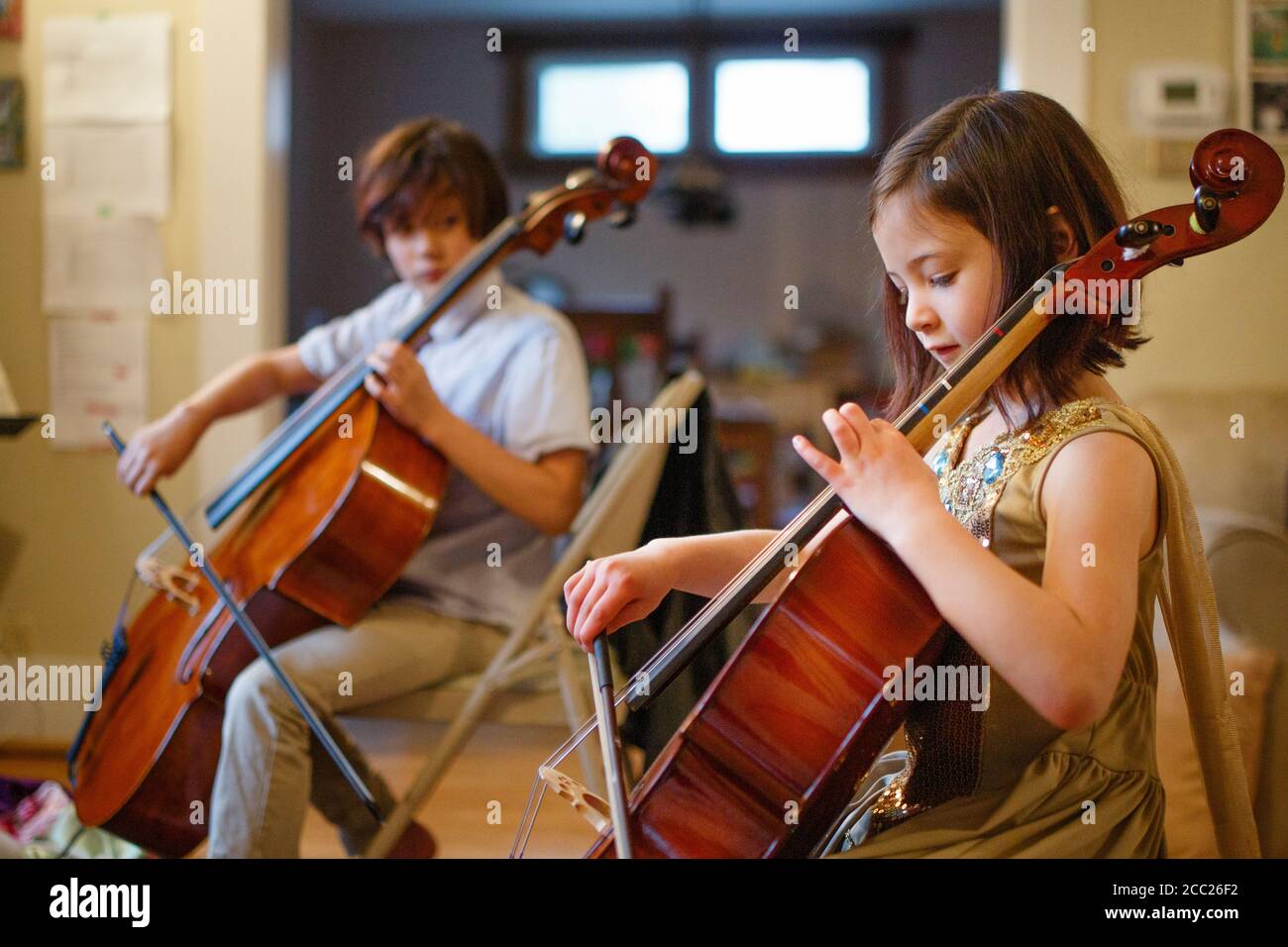 A brother and sister practice cello together in their living room Stock ...