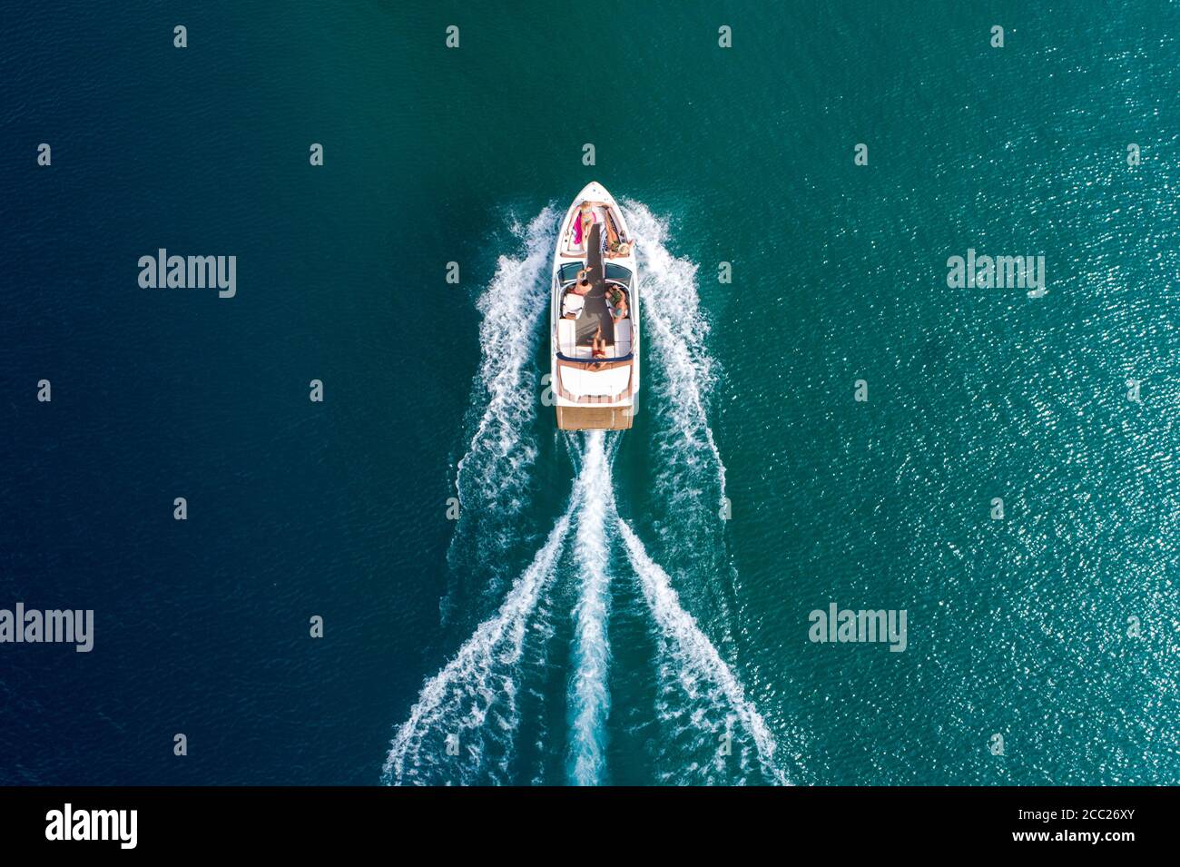 An aerial overhead view of a boat cruising on the beautiful, blue ...