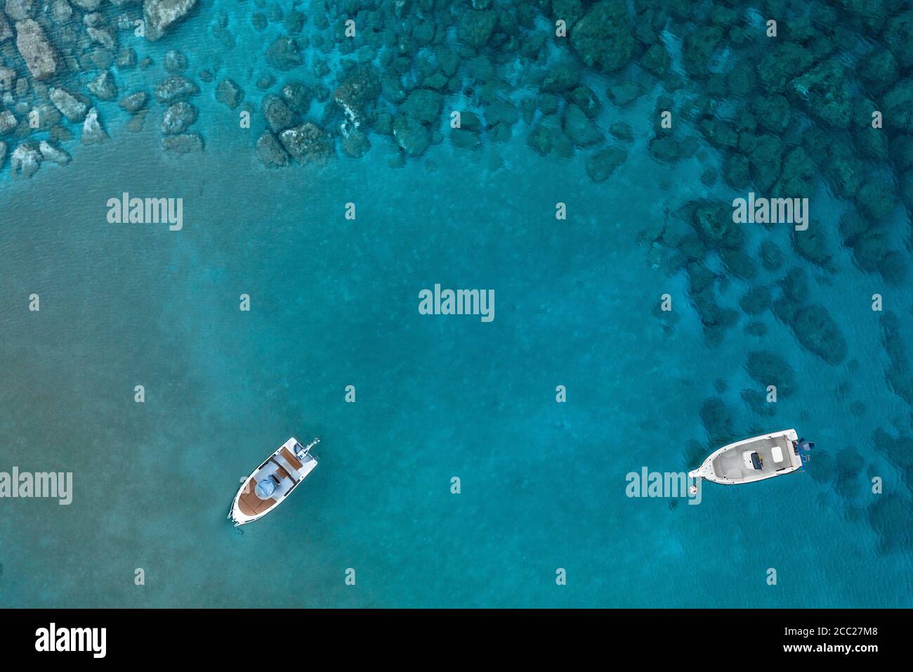 Aerial shot of boats on the sea surrounded by rocks under the sunlight ...
