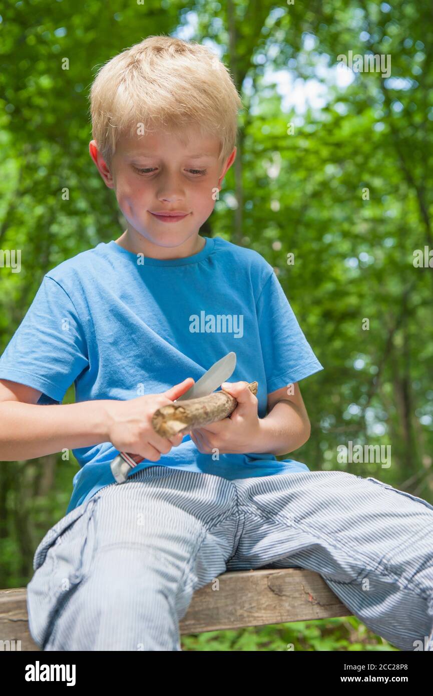 Germany, Bavaria, Munich, Boy carving branch, smiling Stock Photo - Alamy