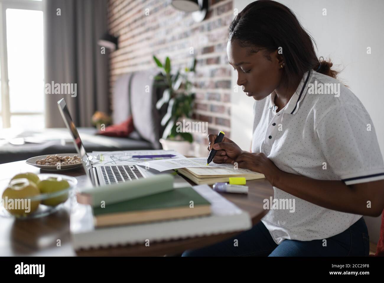 African American woman making marks on paper while preparing for exam ...
