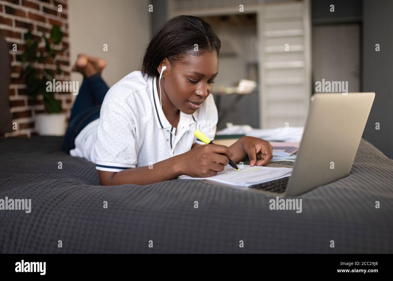 African American woman making marks on paper during online lesson on ...