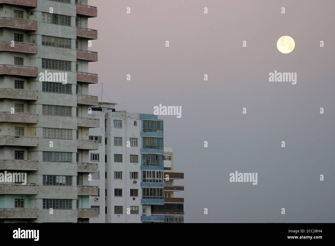old living blocks in front of a dull gray sky with a full moon, Havana ...