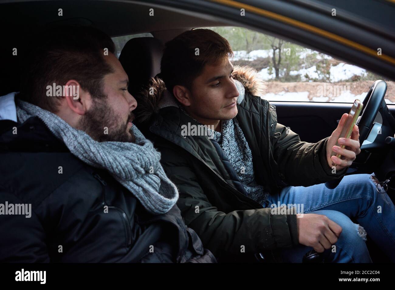 Two young men look at a phone inside a car. Concept of route finding ...