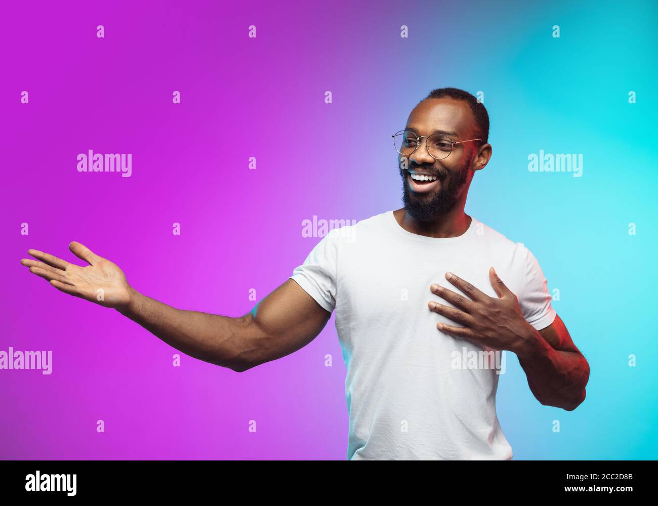 Pointing, showing. African-american young man's portrait on gradient ...