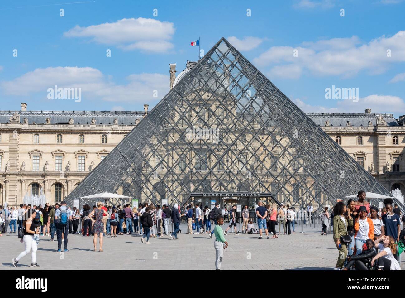 Louvre museum Paris with visitors at bright sunny day. People standing ...