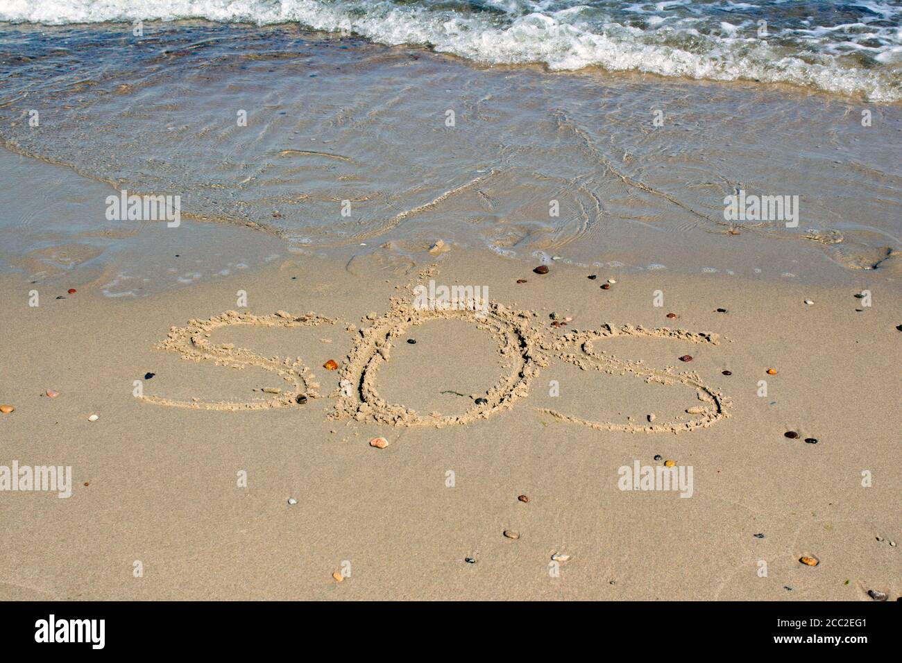 SOS - word drawn on the sand beach with the soft wave Stock Photo - Alamy