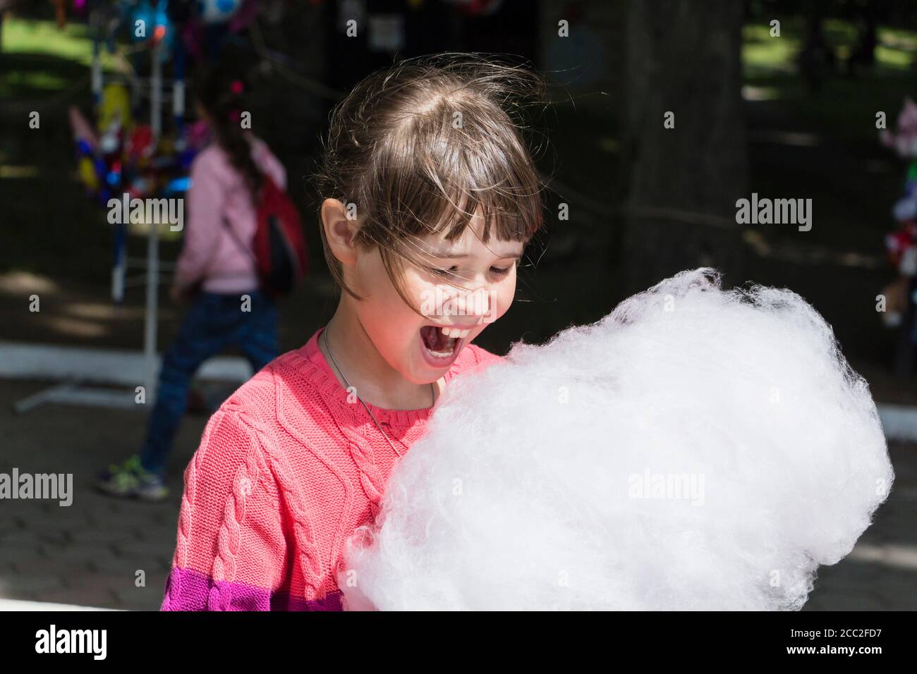 Young girl eating cotton candy in the park Stock Photo - Alamy