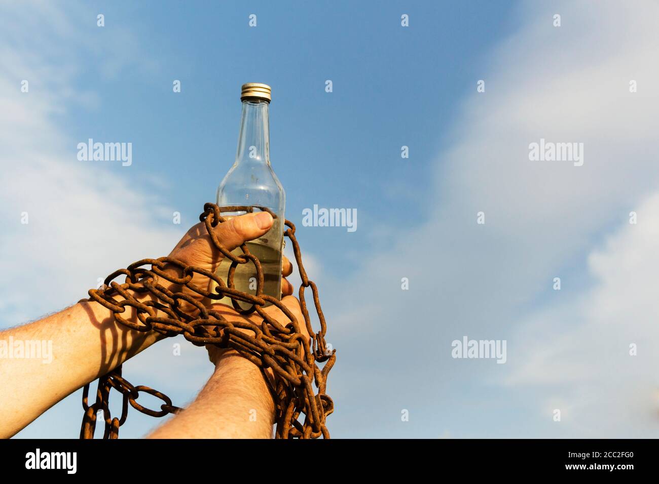 Hand chained to a bottle of alcohol, against the blue sky Stock Photo ...