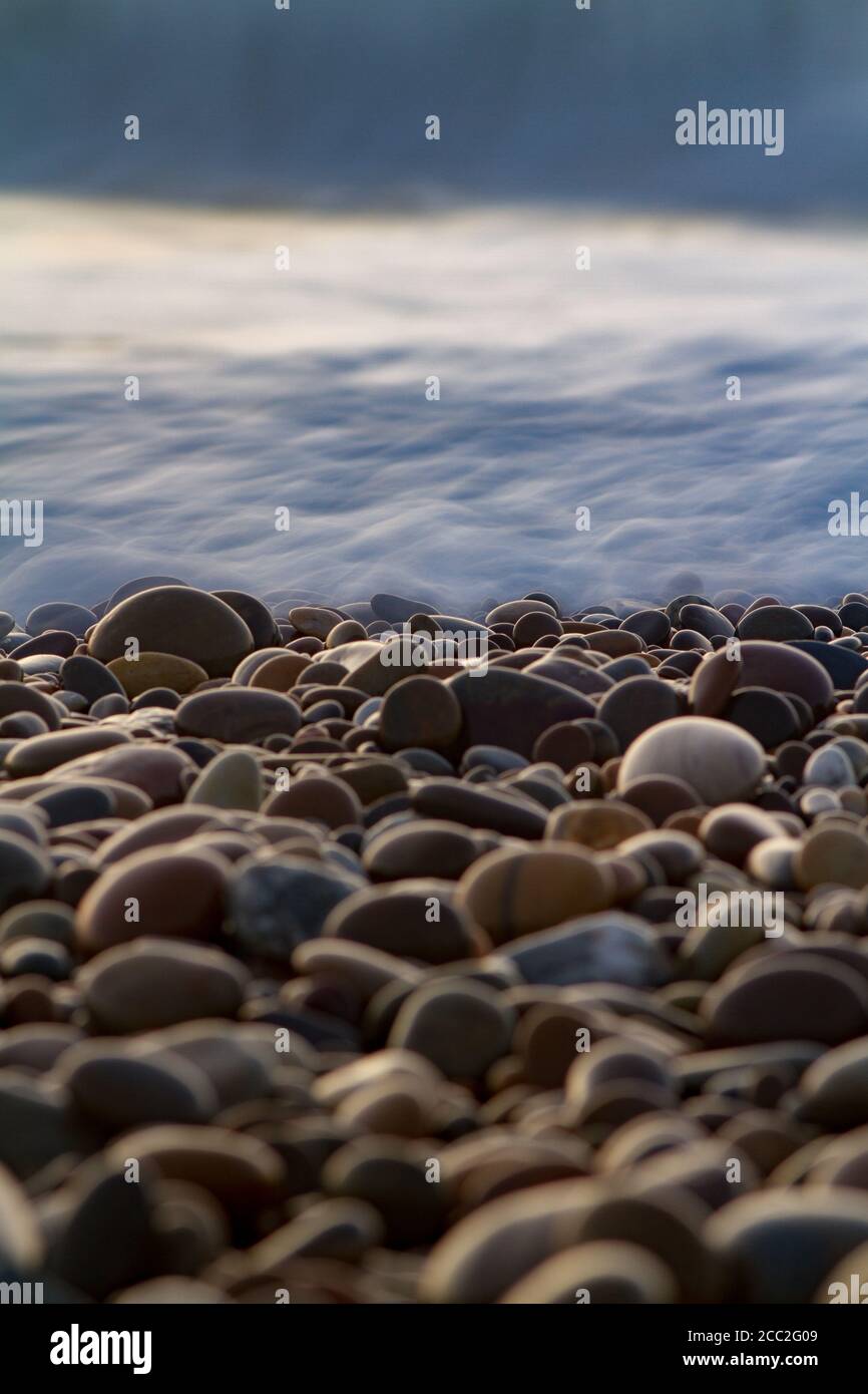 Vertical high angle shot of pebbles on the body of the foamy sea Stock ...