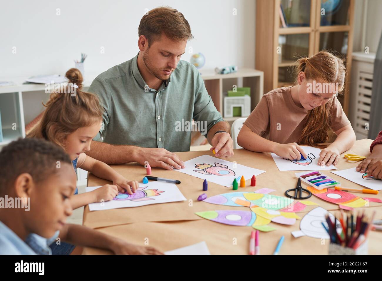 Portrait of male teacher working with multi-ethnic group of children ...