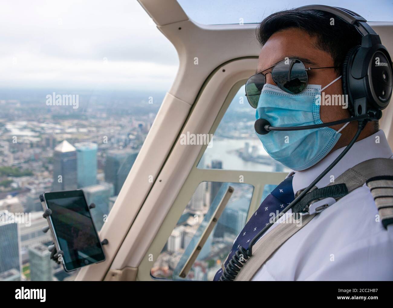 Horizontal portrait of a pilot wearing a face mask flying a helicopter ...