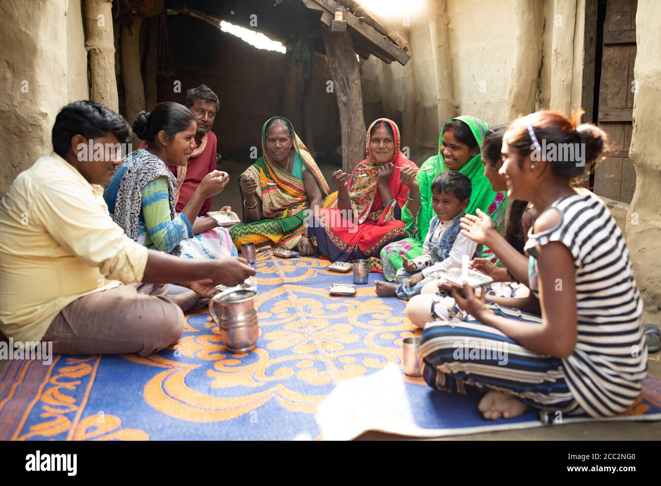 A family sit together in their home courtyard eating a meal together in ...