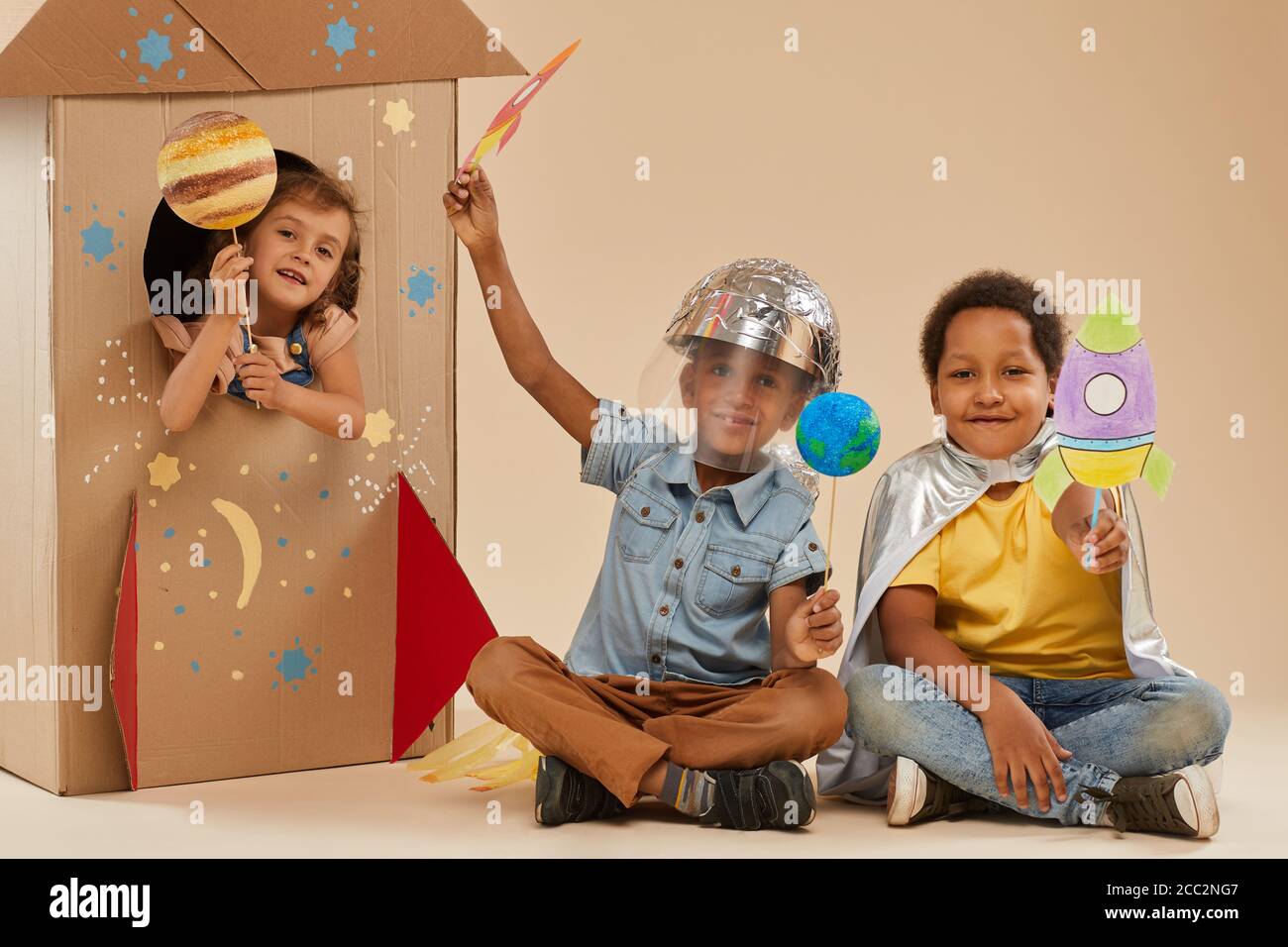 Full length portrait of cute children playing astronauts while sitting ...