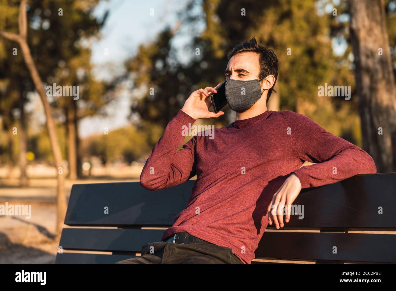 Shot of a male with a mask sitting on the bench in a park - the new ...