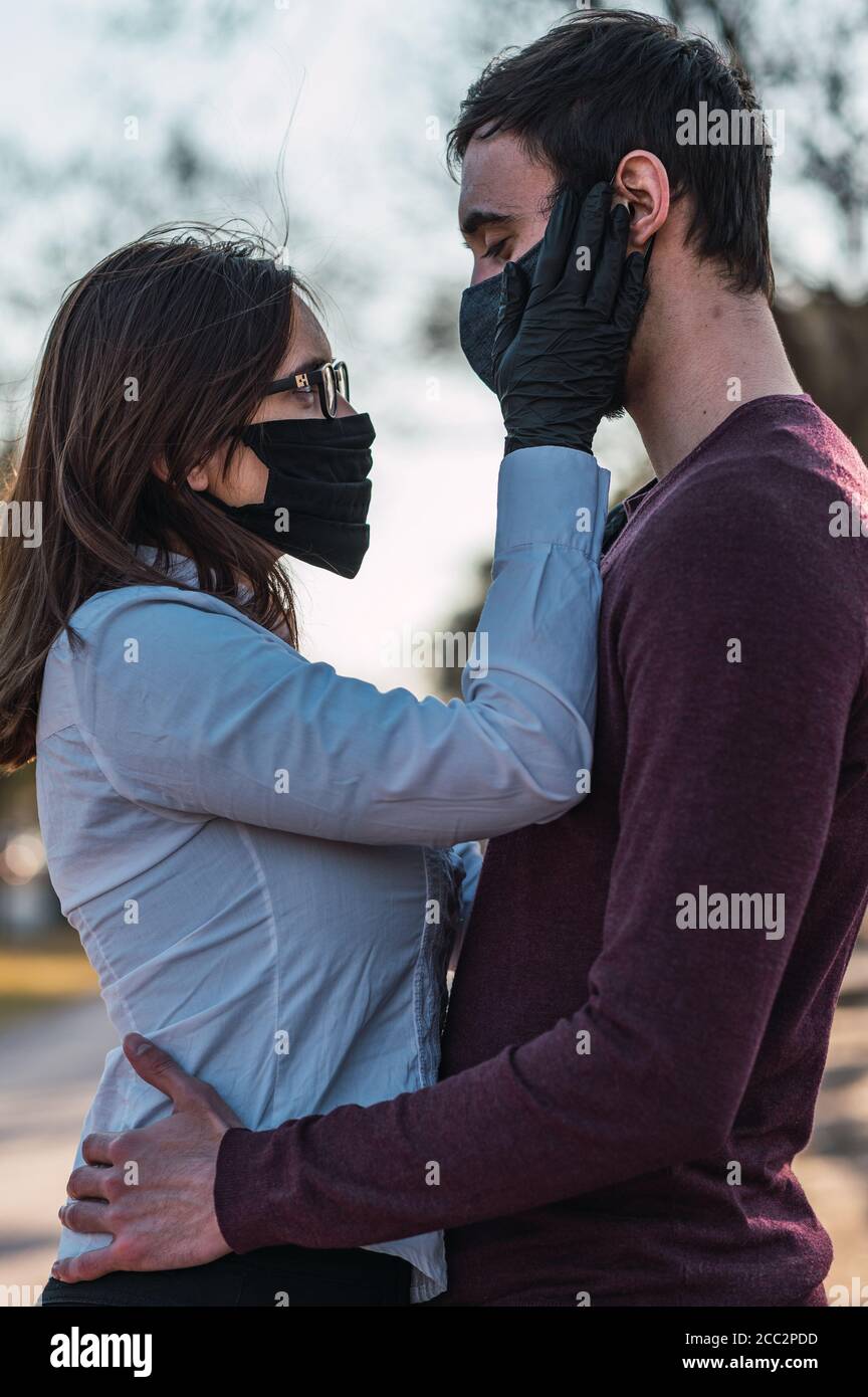 Shot of a couple with masks hugging each other in a park - the new ...