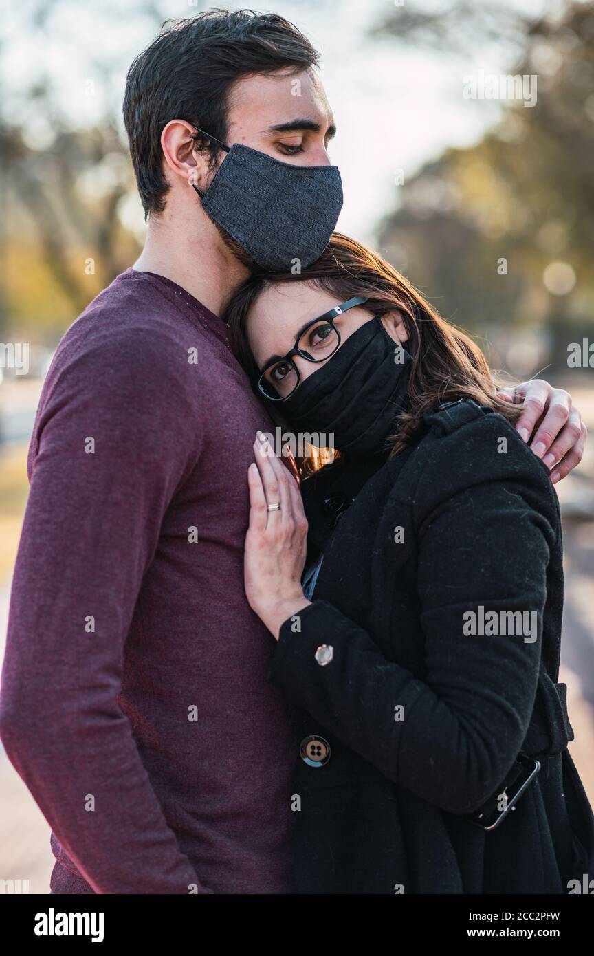 Shot of a couple with masks hugging each other in a park - the new ...