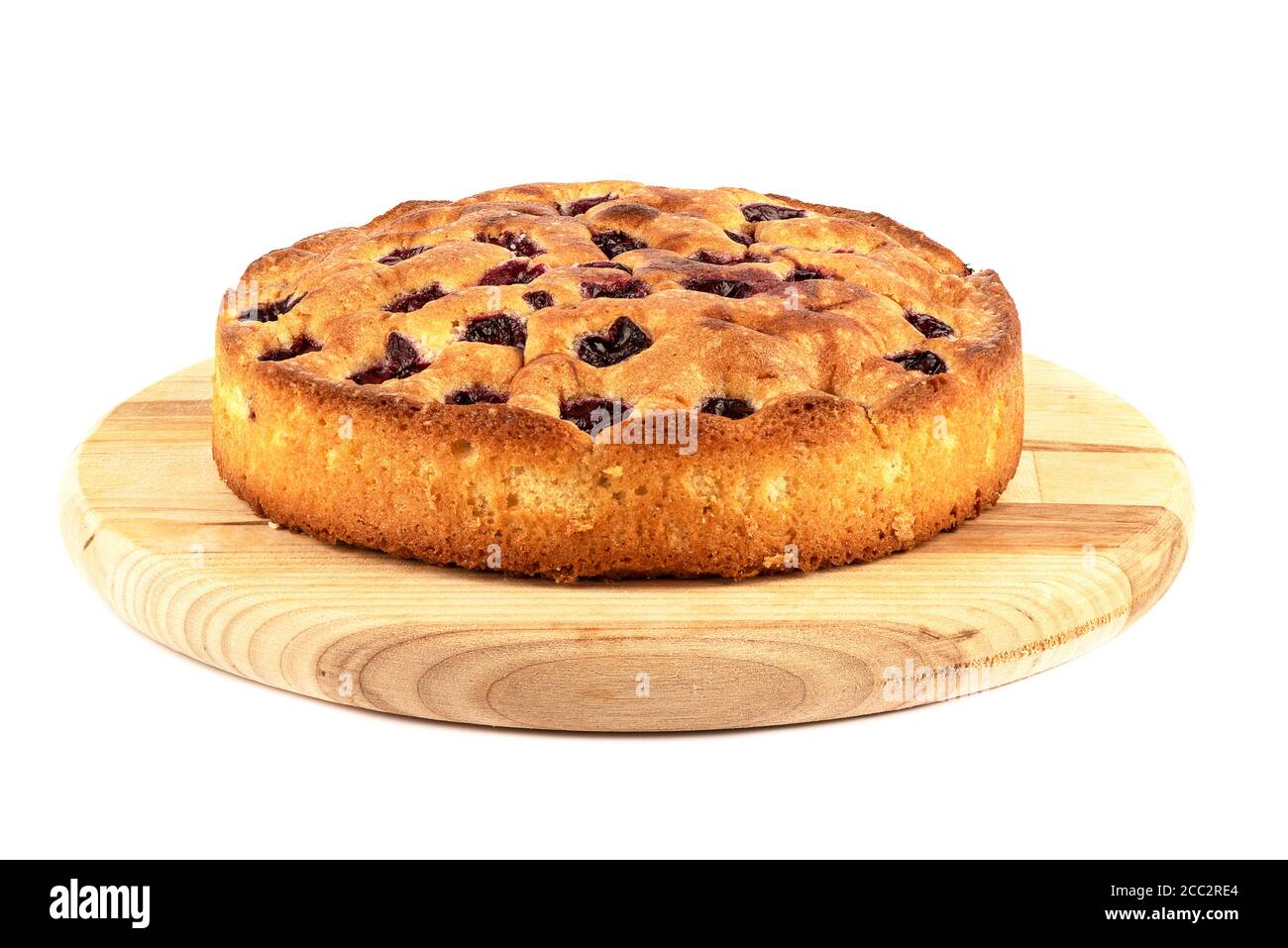 A whole pie with cherries on a cutting board over a white background ...
