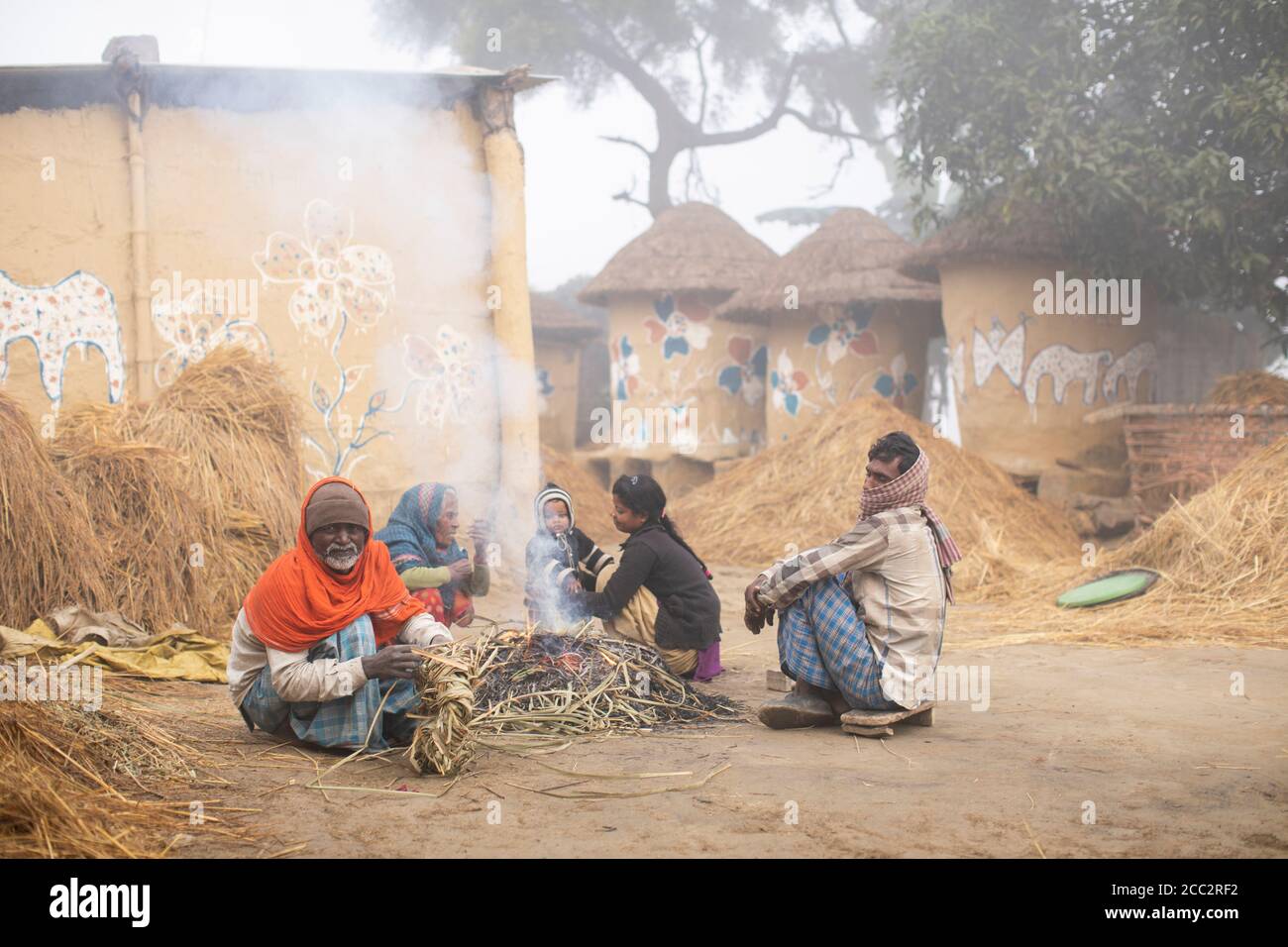 A family warm themselves by a fire outside their home in the Gandak ...