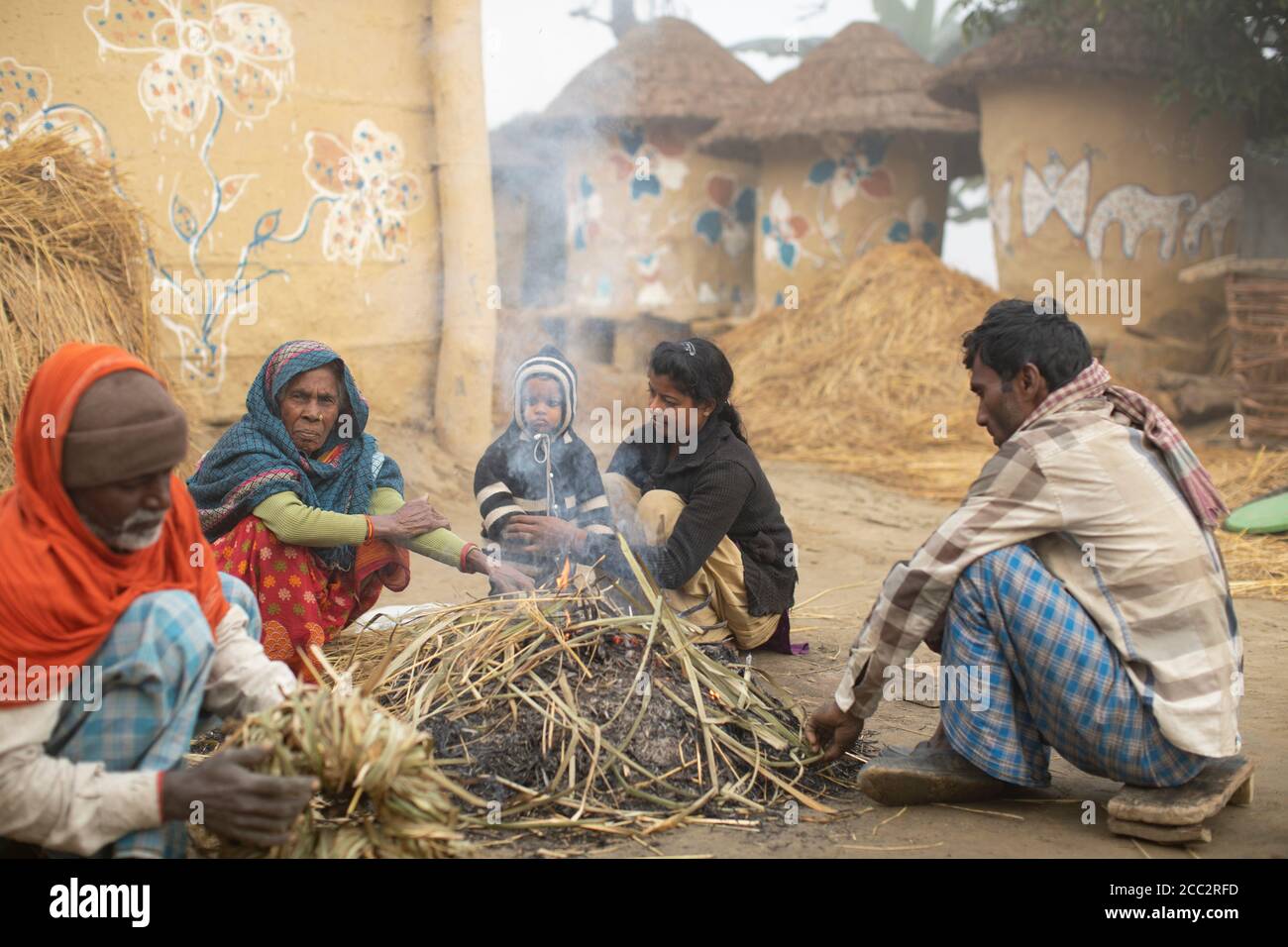 A family warm themselves by a fire outside their home in the Gandak ...