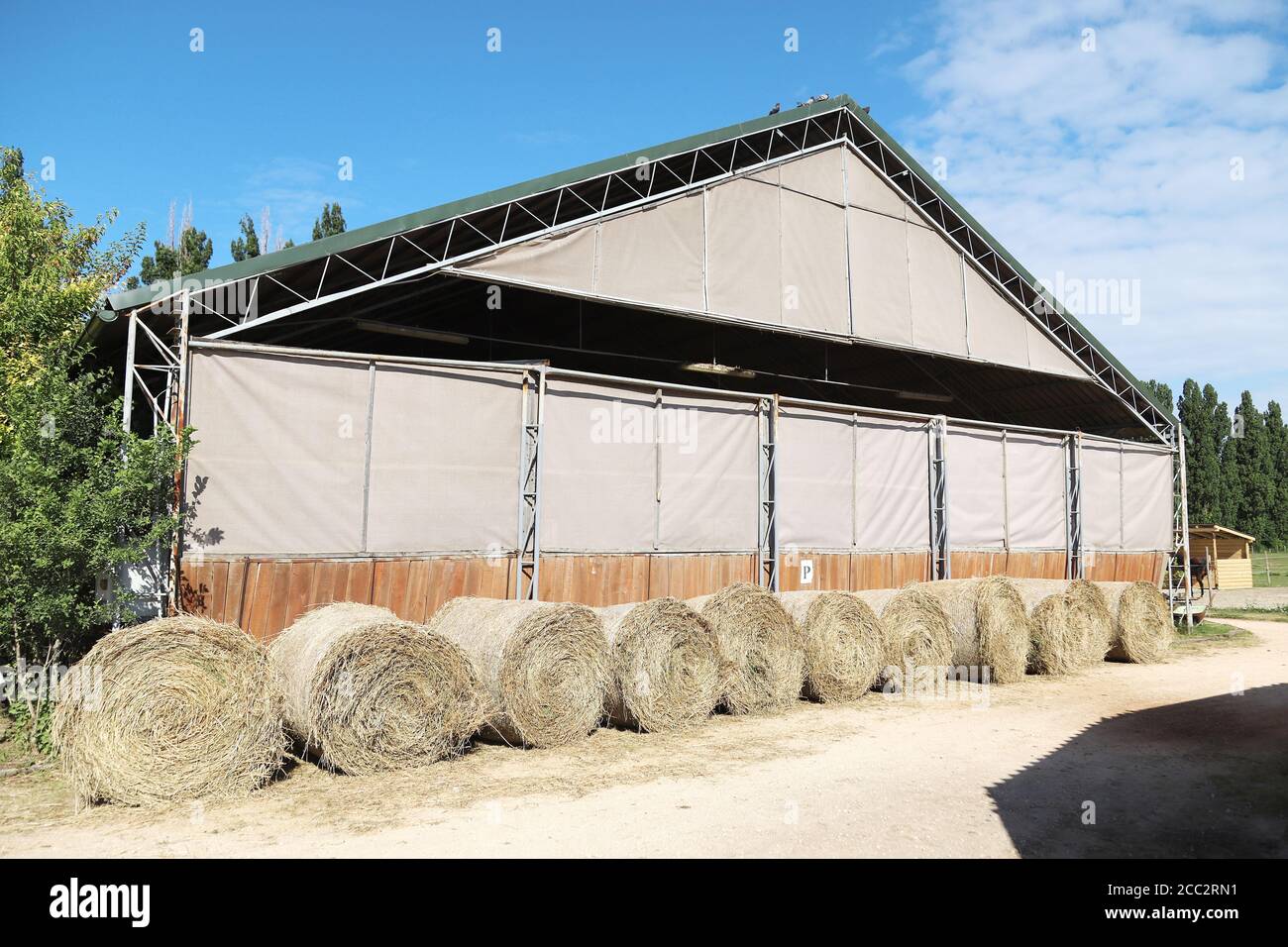View of a rural animal farm with hay bales after harvest. Hay roll ...