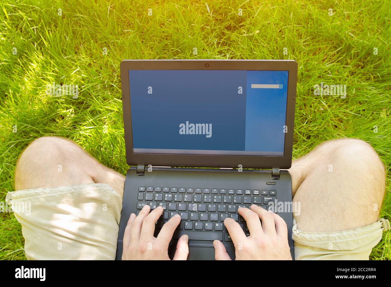 Laptop on man lap on the green grass. Work outdoors Stock Photo - Alamy