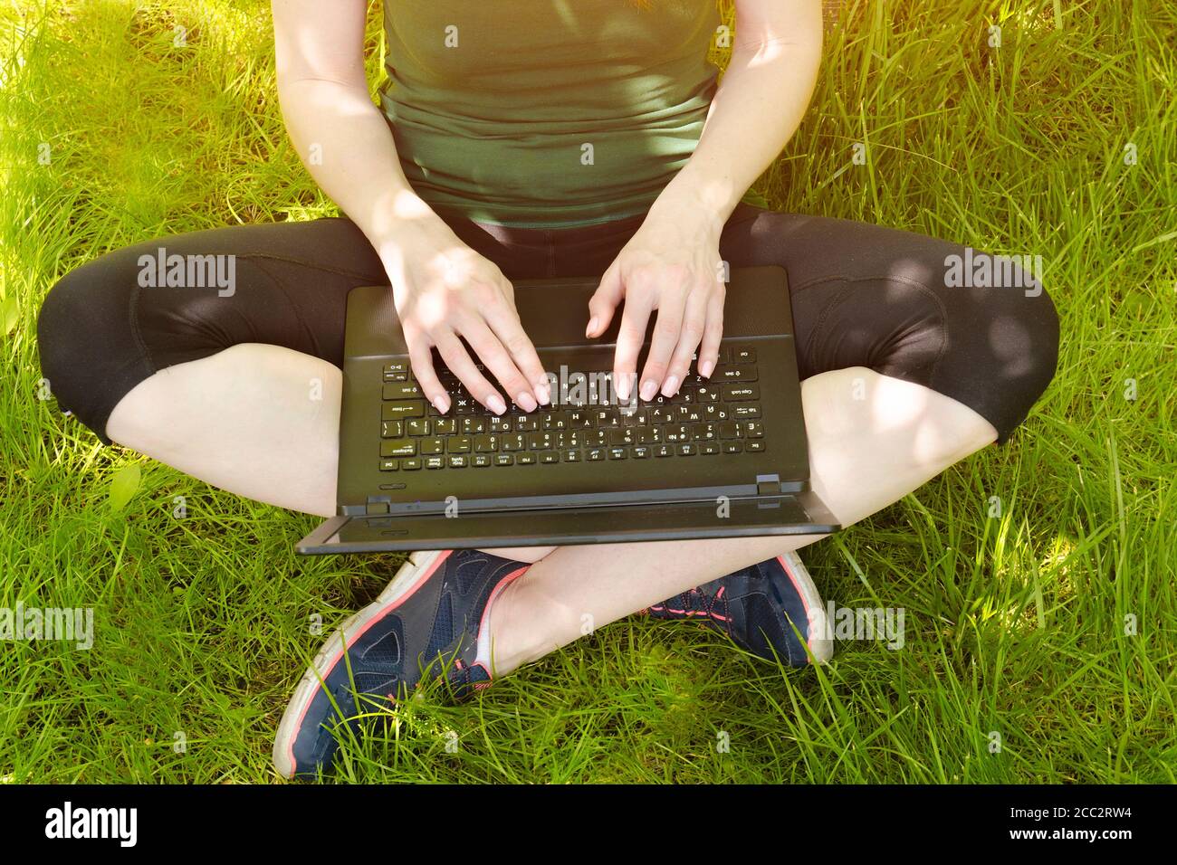 Laptop on girl lap on the green grass. Top view Stock Photo - Alamy
