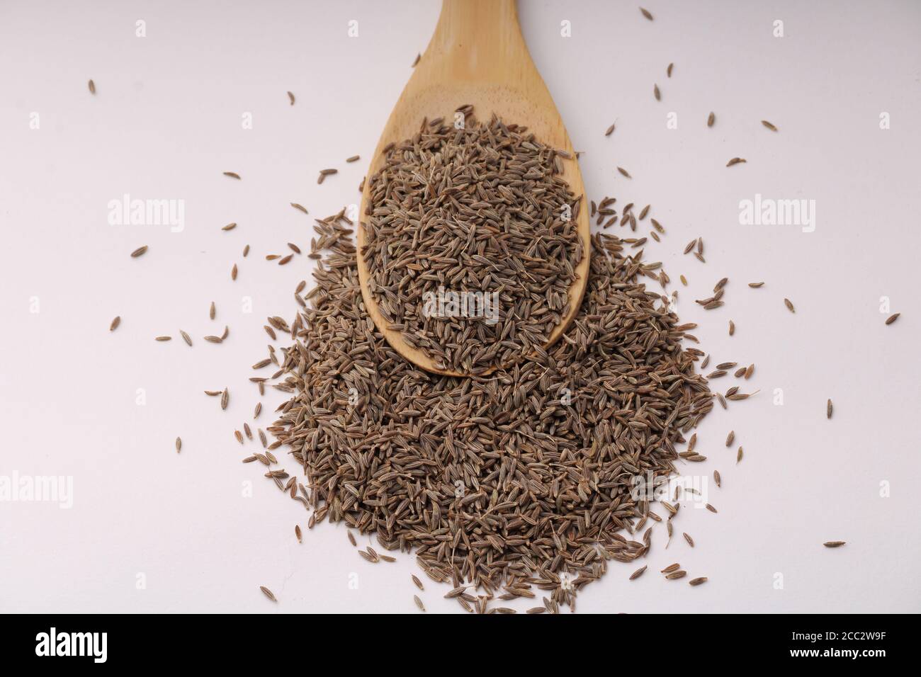 Wooden spoon full of cumin seeds isolated over the white background ...