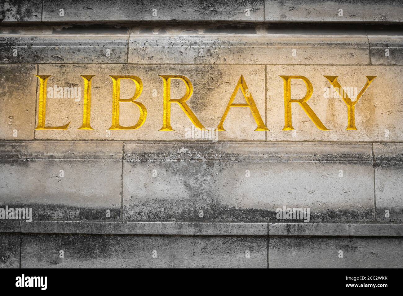 Public library exterior. Golden text engraved on a concrete wall ...