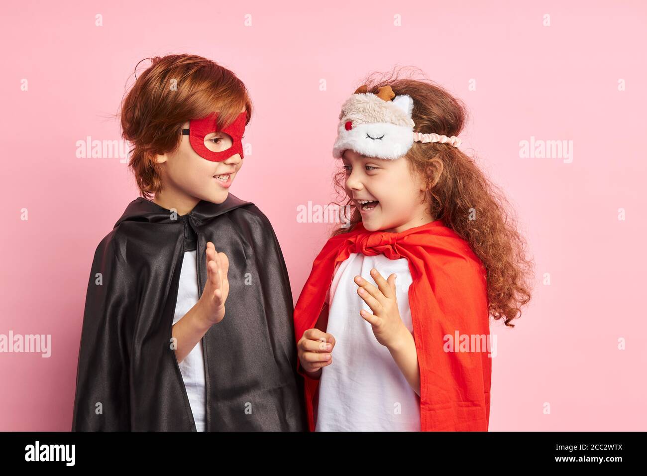 Little boy and girl stand together isolated over pink background, play ...
