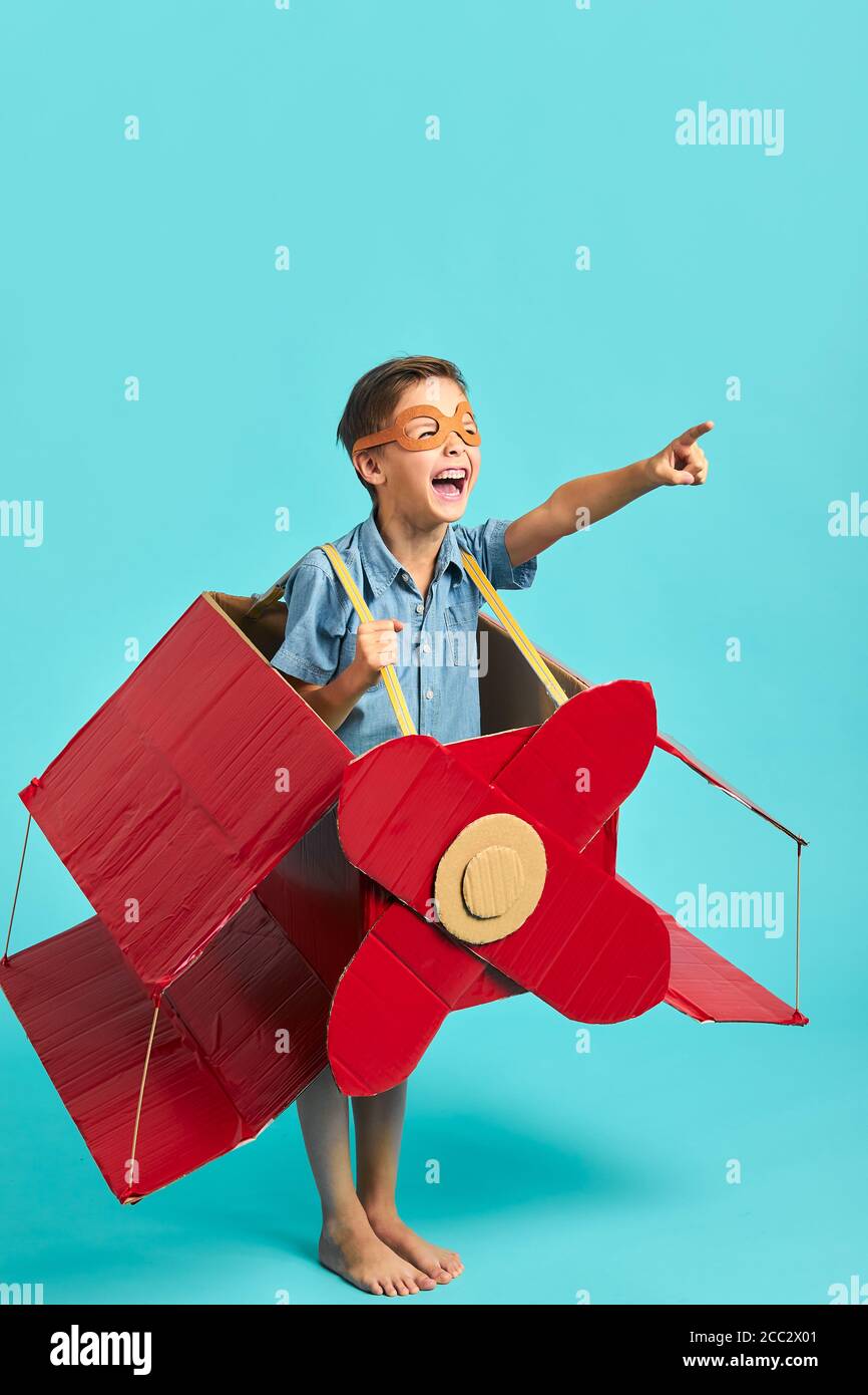 Happy caucasian boy flying on red carboard airplane, happy boy in ...