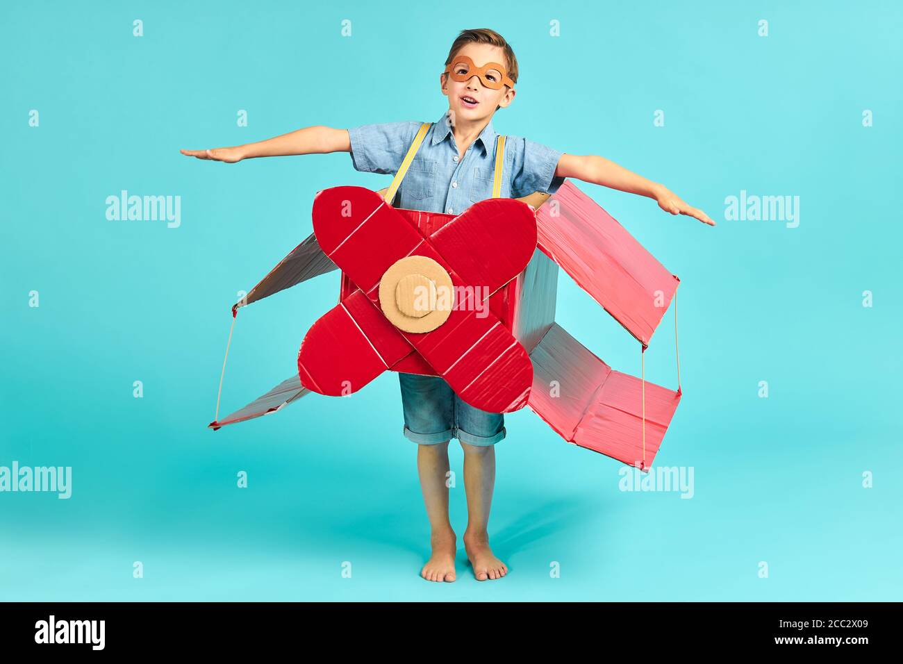 encouraged boy with open arms at sky while flying on cardboard box in ...