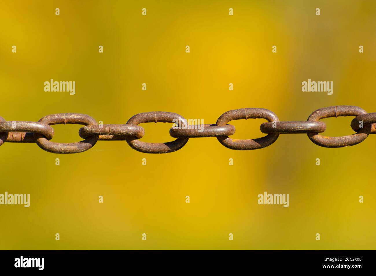 Old metal chain on a blurred yellow background Stock Photo - Alamy