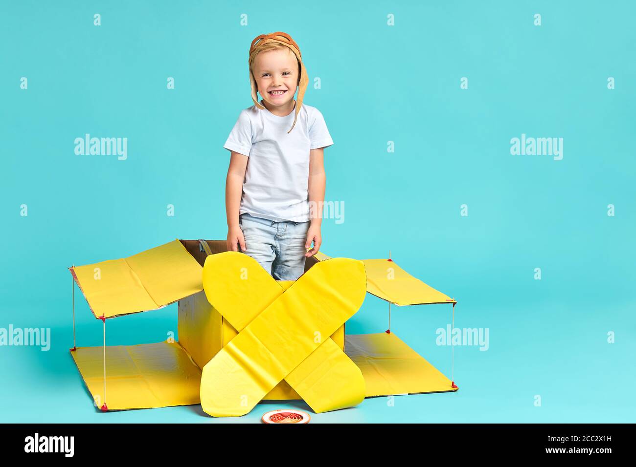 Small little boy with blond hair stand wearing toy yellow airplane ...