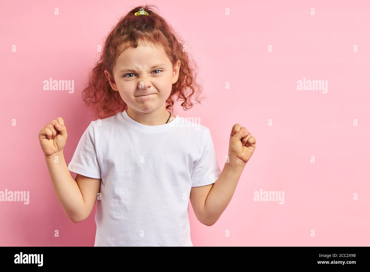Emotional, irritated little girl wearing white t-shirt stand isolated ...