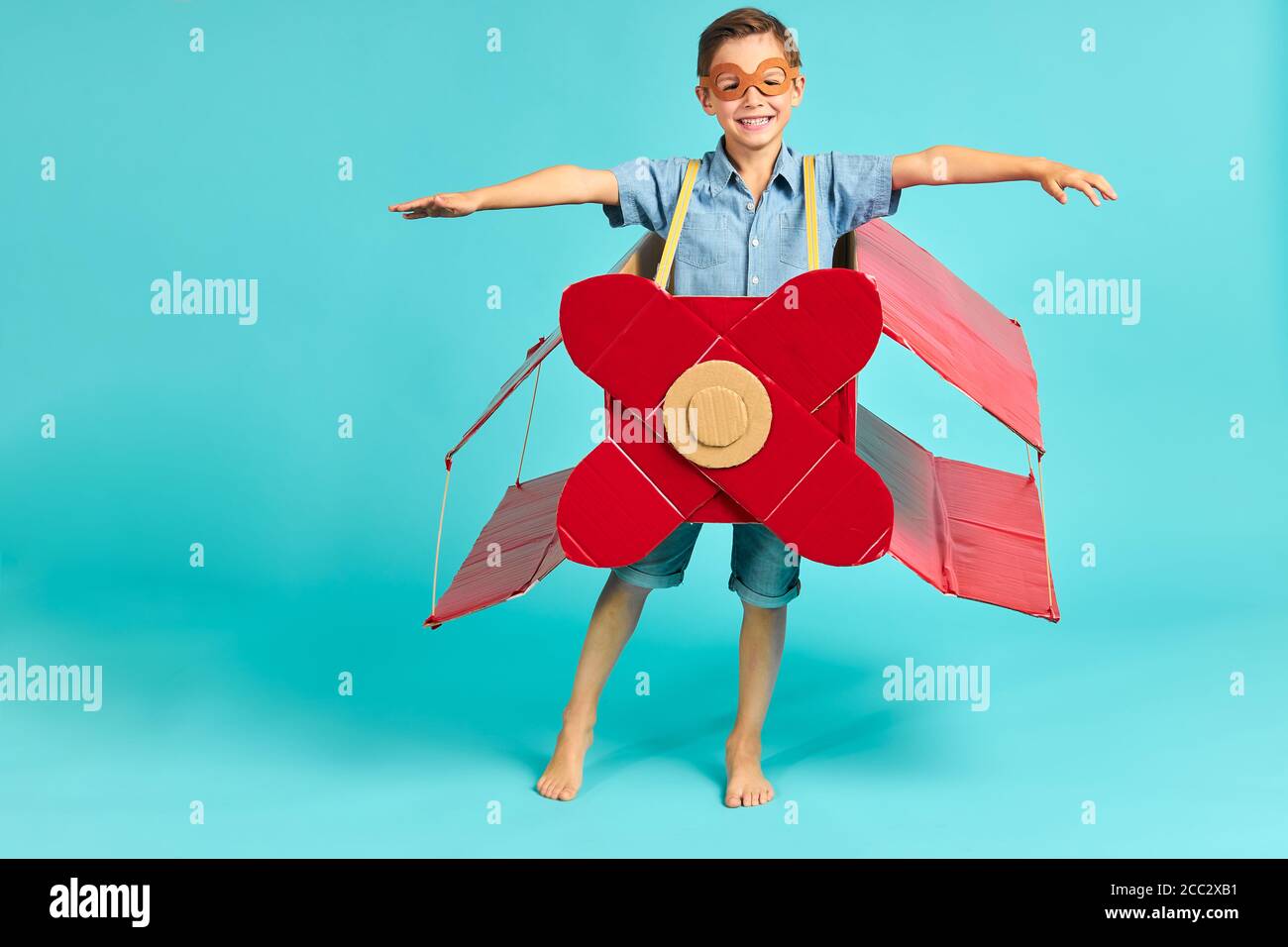 Happy smiling boy with open arms at sky while flying on cardboard box ...