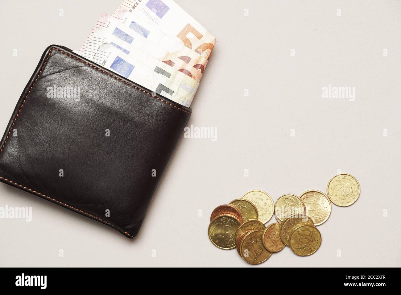 man's wallet full of 50 euro bills next to coins. concept of economic ...